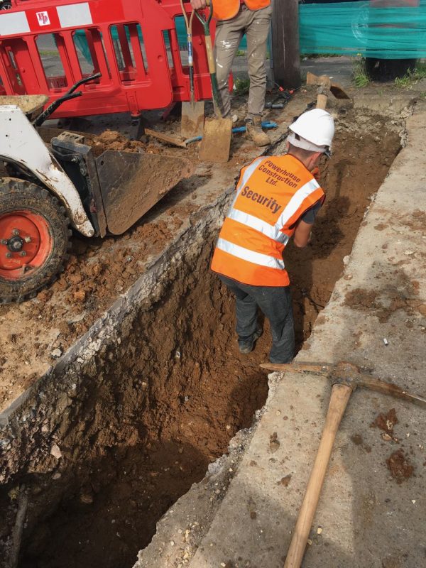 Hand digging trench for utility services around existing pipework and ...